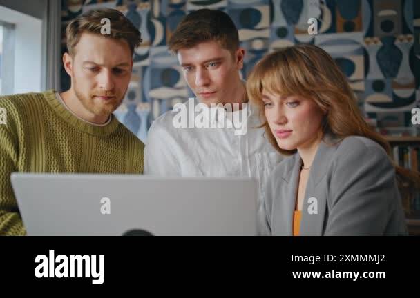 Confident team watching laptop screen discussing together at office ...