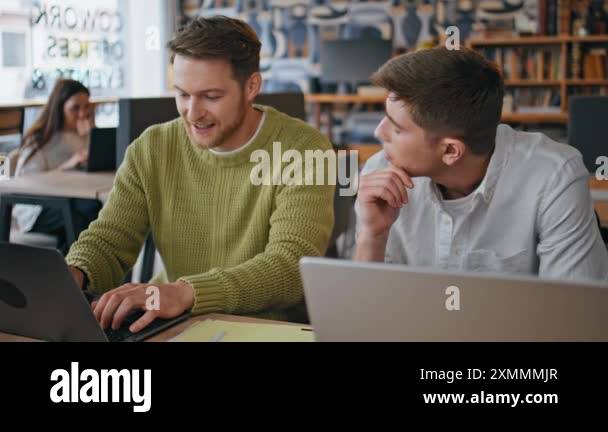 Creative colleagues using computers collaborating in boardroom at ...