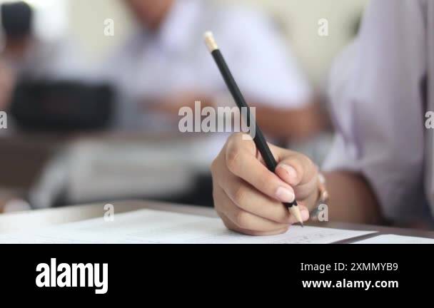 Close up hand of student reading and writing exam answer sheets ...