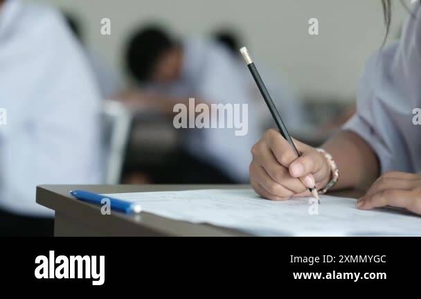 Close up hand of student reading and writing exam answer sheets ...