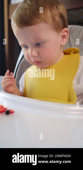 Vertical footage of curious little boy in high chair eats fresh ...
