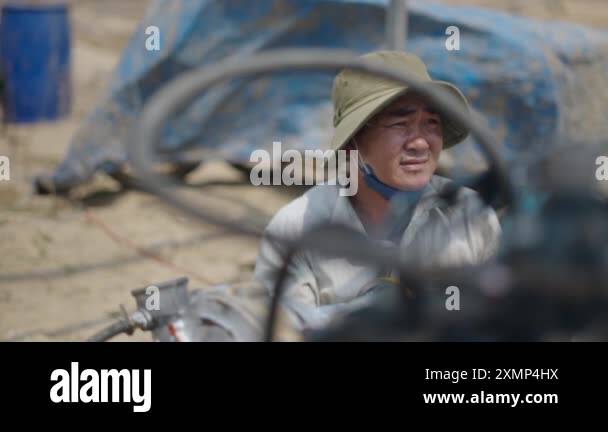 slow motion Vietnamese mechanic with a big hat working repairing the ...
