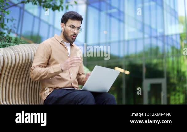 Disappointed businessman read bad news on laptop while sitting on bench ...