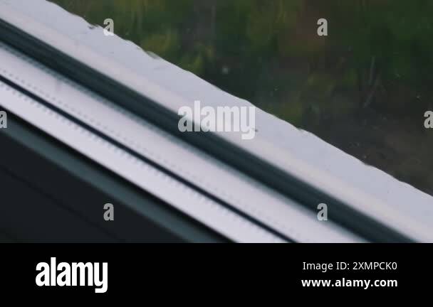Slow motion side view footage of rain falling on a window sill ...