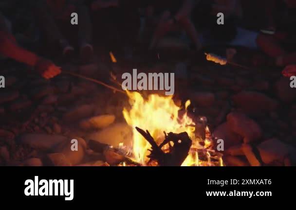 Gathered around a campfire in the great outdoors, friends enjoy ...