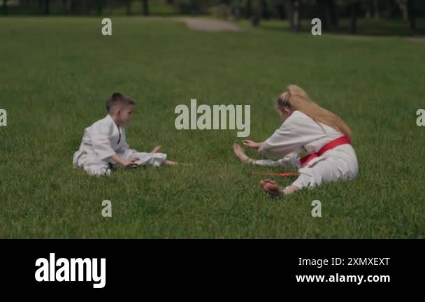 A mother and her son practice karate together in the park. They are ...
