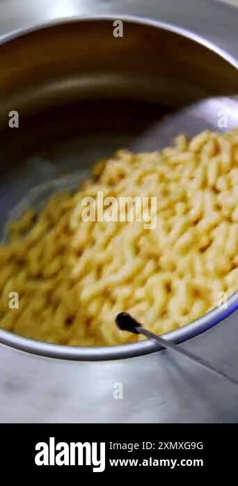 Spinning metal tank filled with yellow crispy snacks. Pulverize device ...