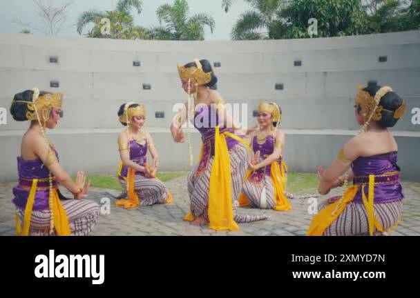 A traditional dance performance featuring five dancers in vibrant costumes. The central dancer ...