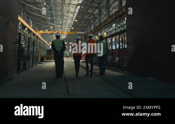 Back view of four heavy industry technicians in uniform and helmets ...