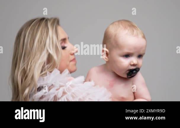 Loving mother in white robe waving her little child. Cute baby with ...