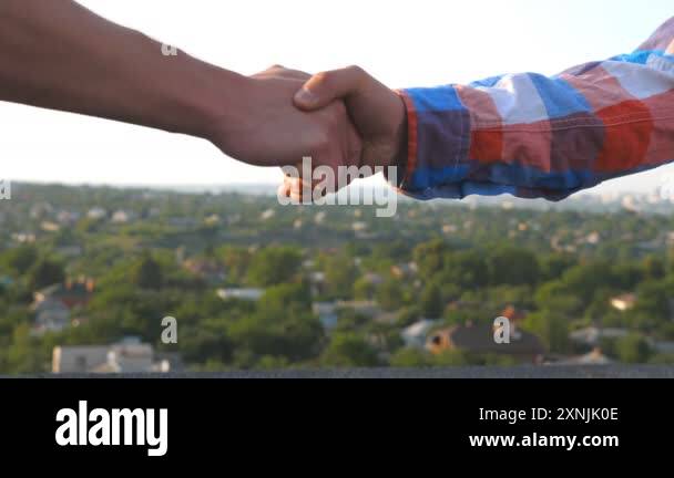 Two friends shaking hands on blurred cityscape background. Close up of ...