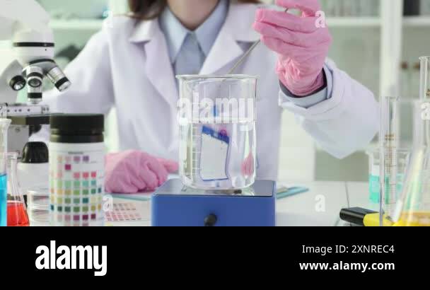 Scientist mixes bright pink reagent in beaker with water. Professional ...