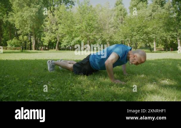Motivated active sporty fit mature man practicing advanced push up ...