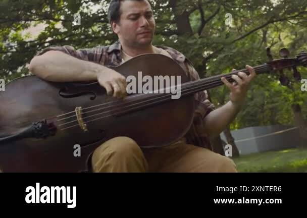 Zoom shot of expressive male musician holding cello like guitar ...