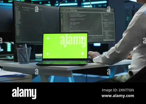 Zoom in on green screen laptop used by data center worker troubleshooting issues. Engineer uses ...