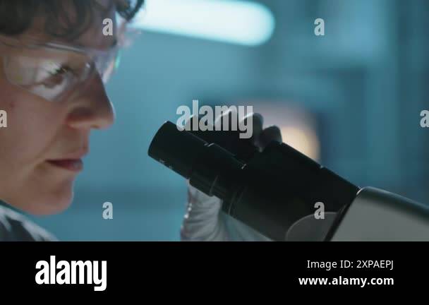 Close-up side shot of face of Caucasian female scientist bending down ...