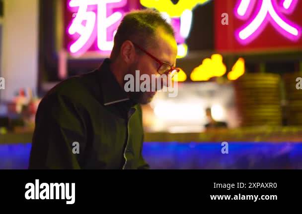 Man transfixed by pinball machine, neon lights reflect addiction. Hes ...