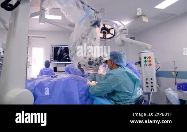 Professional neurosurgeons operating the patient looking at microscope ...