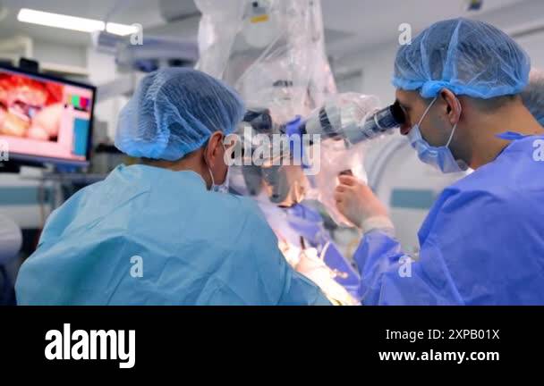 Rear view of medics looking intently into the powerful microscope ...