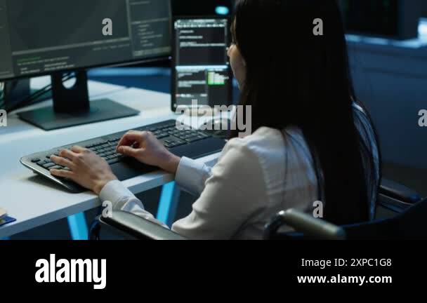 Person with paraplegia working in inclusive server hub workspace, typing on PC. Woman in ...