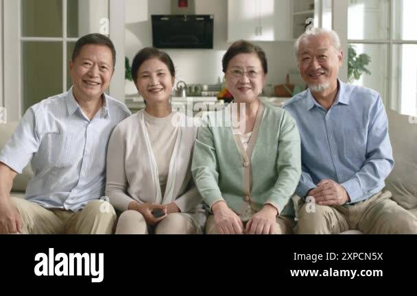 two happy senior asian couples sitting on couch at home watching tv together Stock Video Footage ...