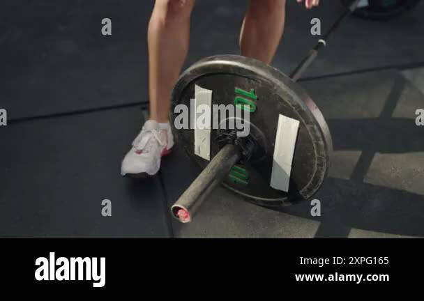 Hands in wrist straps secure weight plate for lifting session. Close-up, athlete removes clamp ...