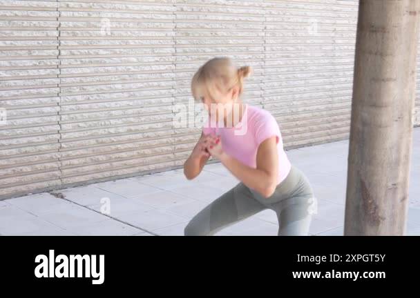 A healthy young woman is doing squats and stretches with a resistance ...