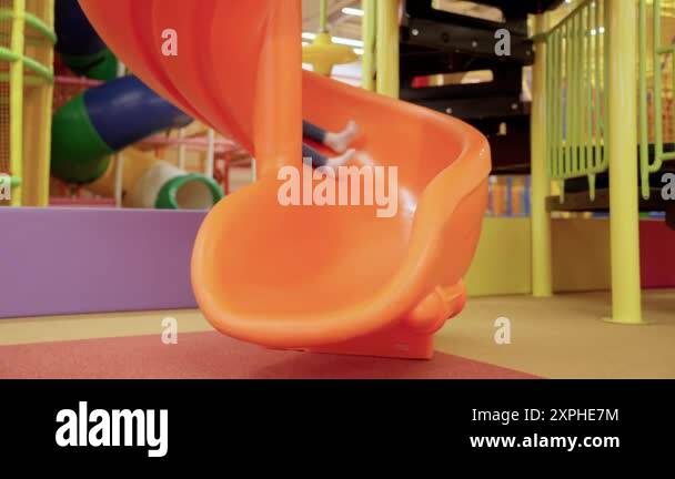 Smiling cute little girl sliding down a slide with hands behind the ...