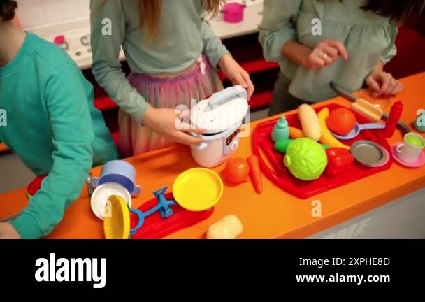 Children playing at the toy kitchen in game center using toy vegetables ...