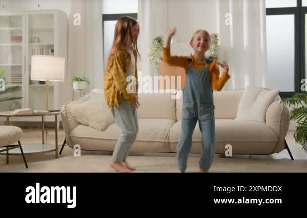 Two carefree Caucasian children little girls sisters laugh jumping ...
