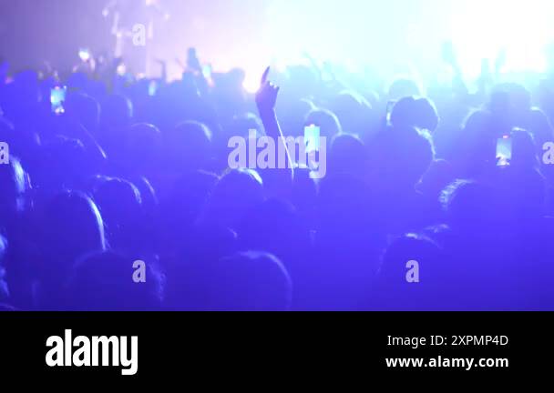 Audience crowd fans with hands up in air silhouette moving in bright ...