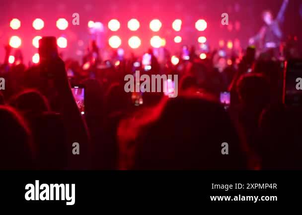 Slow motion closeup of audience crowd fans with hands up in air holding ...