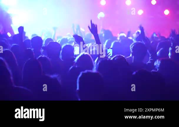 Crowd jumping and waving hands at concert in spotlights light. Fans ...