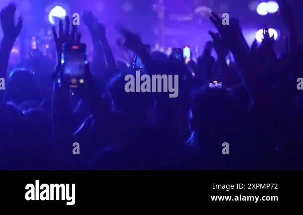 Crowd jumping and waving hands at concert in spotlights light. Fans ...