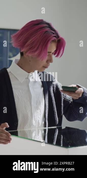 Vertical shot of gen Z Asian man with pink hair taking pictures of ...