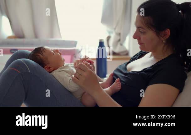 Mother and newborn baby interacting on a bed, gazing at each other with ...
