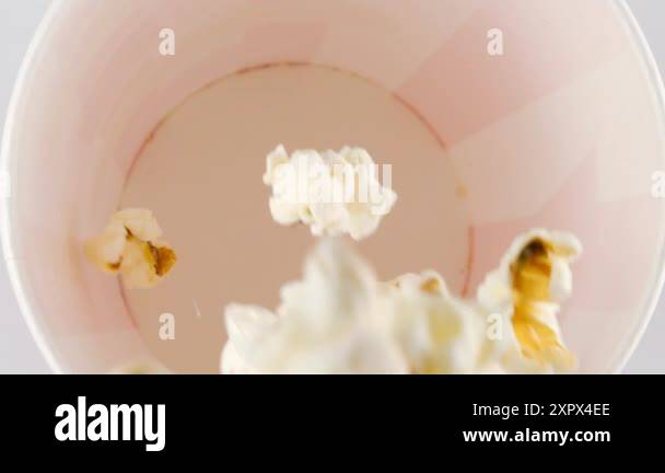 Popcorn grains falling into red and white striped bucket isolated on ...