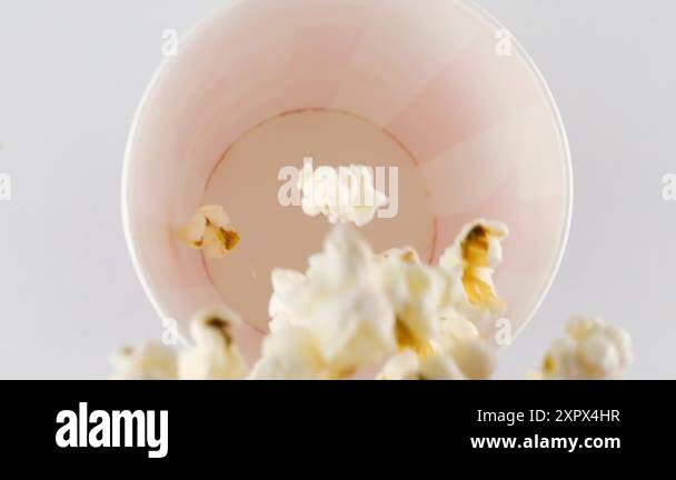 Popcorn grains falling into red and white striped bucket isolated on ...