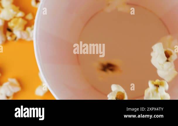Popcorn grains falling into red and white striped bucket isolated on ...