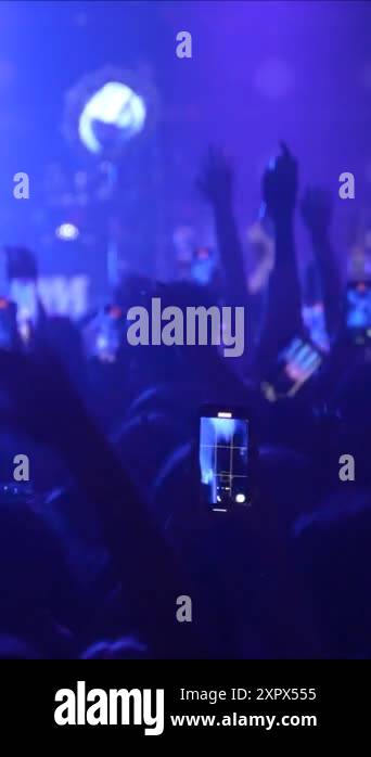 Vertical video slow motion of unrecognizable fans dancing at a concert ...