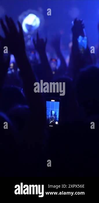 Vertical video slow motion of unrecognizable fans dancing at a concert ...
