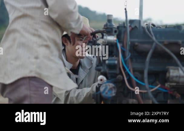 young mechanic with big hat working repairing a boat engine in vietnam ...
