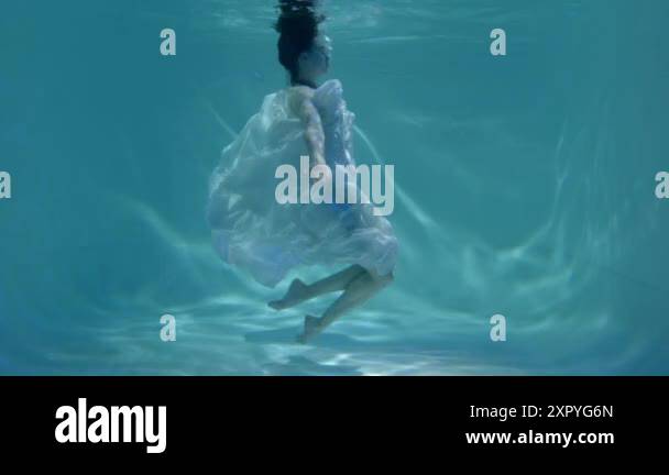 Slim attractive woman with long brown hair in elegant white fluttering ...