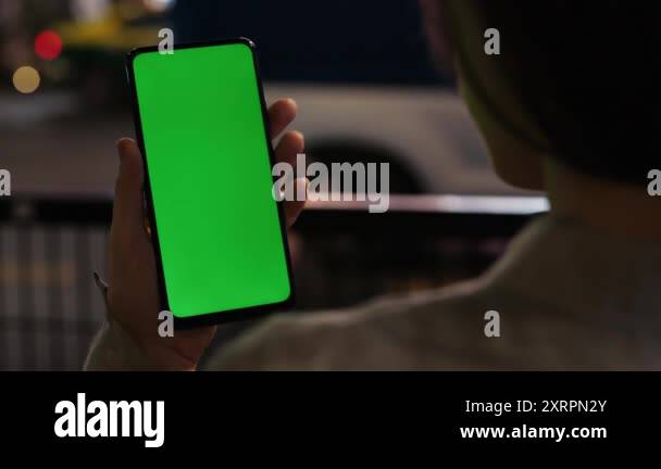 Woman Stands Outside on the Night City and Looks at the Green Screen of the Phone. Female Hands ...
