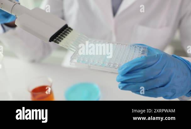 Laboratory worker holds multichannel pipette pouring liquid at ...