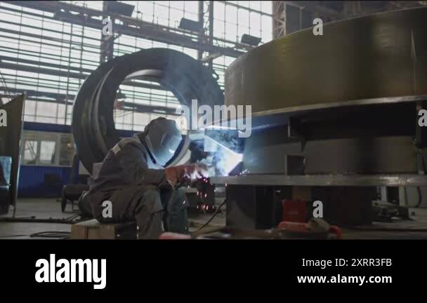 Welder at industrial plant with large metal parts. Stock clip. Welder ...