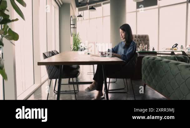 In modern office room young Asian woman working on-line on laptop ...
