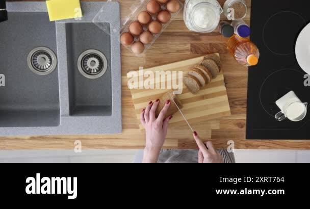 Cutting crusty artisan bread with knife in kitchen, top view. Rule of ...