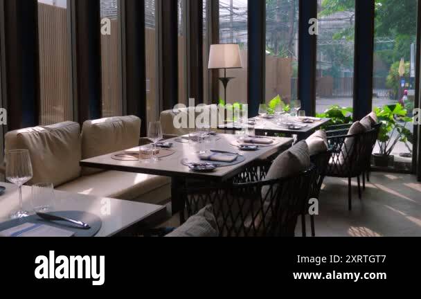 Elegant modern restaurant interior with natural light, empty tables set ...