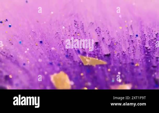 Shimmering paint. Liquid glitter flow. Defocused purple color shiny metallic gold sequin ...